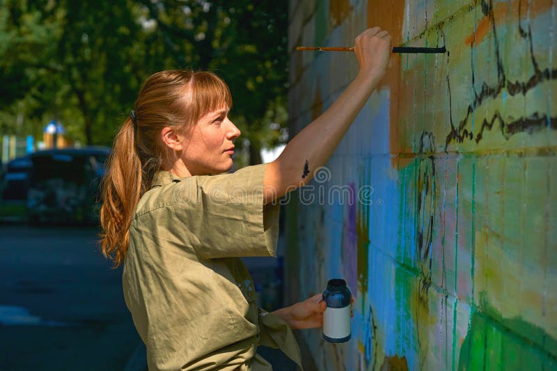 Pretty Graffiti Artist Painter with a Brush on a Stepladder Paints a ...