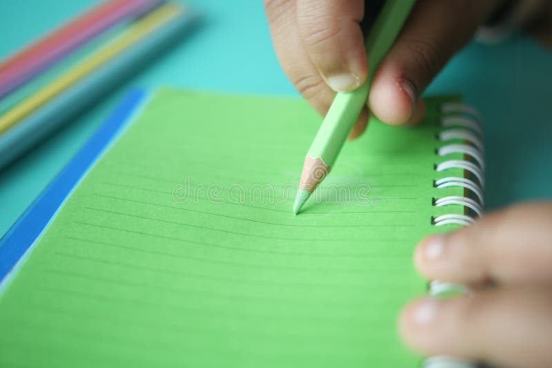Writing with Green Pencil on Lined Notebook in a Bright Setting Stock ...