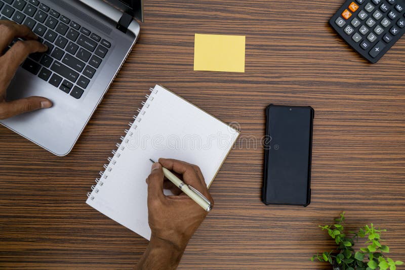 Writing on a Notepad and Typing on a Keyboard while Working on a ...