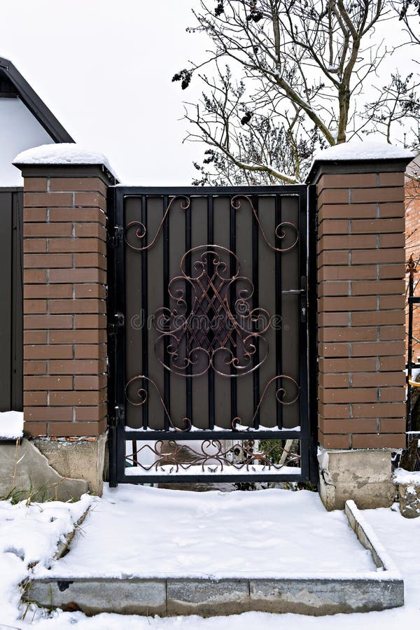A Wrought Iron Gate in Front of a Brick Wall Covered in Snow Stock ...