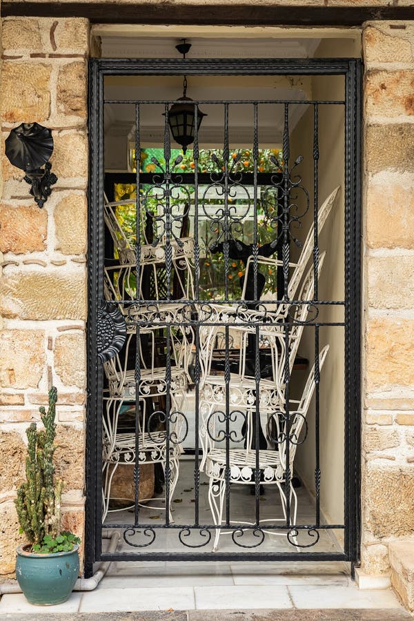 Wrought Iron Gate with Stacked White Furniture in Rustic Stone Entryway ...