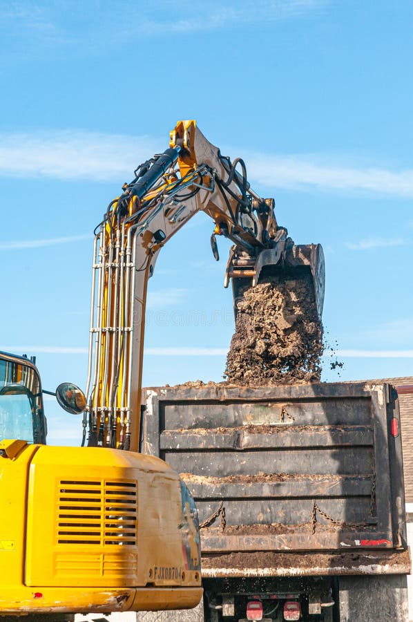 A 4x4 Backhoe Loader, Dumping Dirt into a Commercial Dump Truck Stock ...