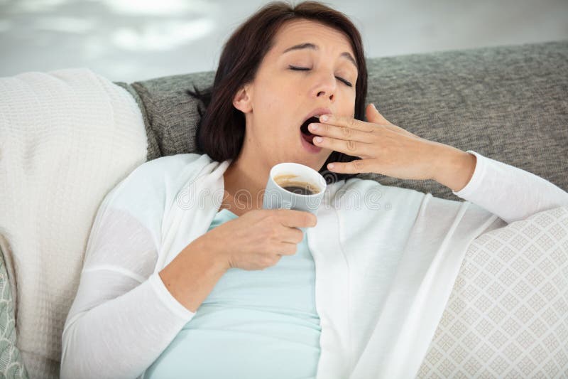 Yawning Woman on Sofa Holding Coffee Stock Image - Image of stimulant ...