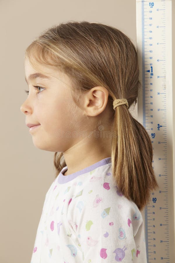 Girl Measuring Height Standing Against Wall at Home Stock Photo - Image ...