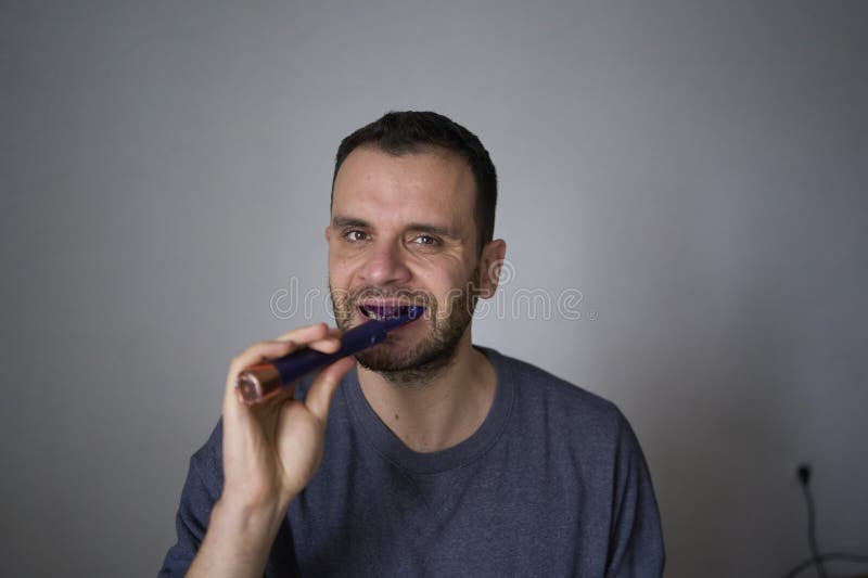 A 30-year-old Man Brushes His Teeth with Purple Toothpaste Using an ...