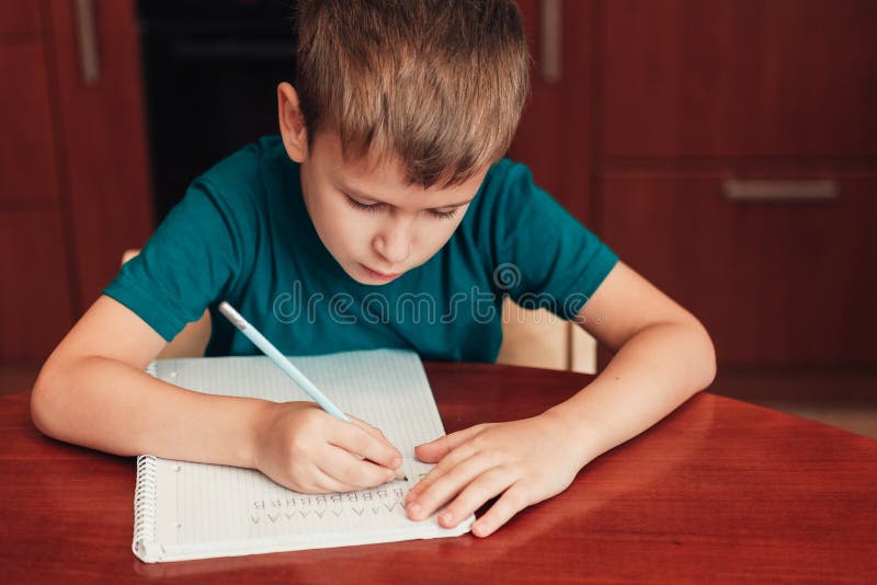 7 Years Old Child Writing Letters in Notebook Sitting by Table Stock ...