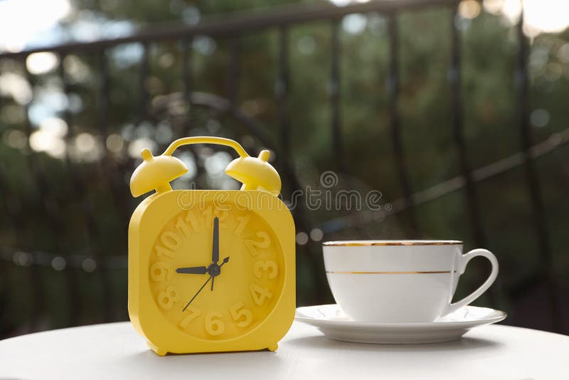 Yellow Alarm Clock and Cup with Hot Drink on White Table in Morning ...