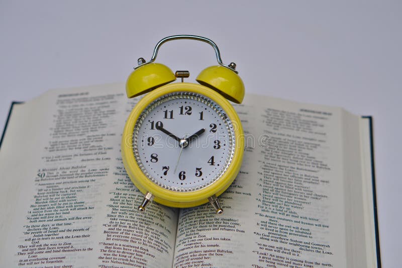 Yellow Alarm Clock on the Open Bible on a White Surface Stock Image ...