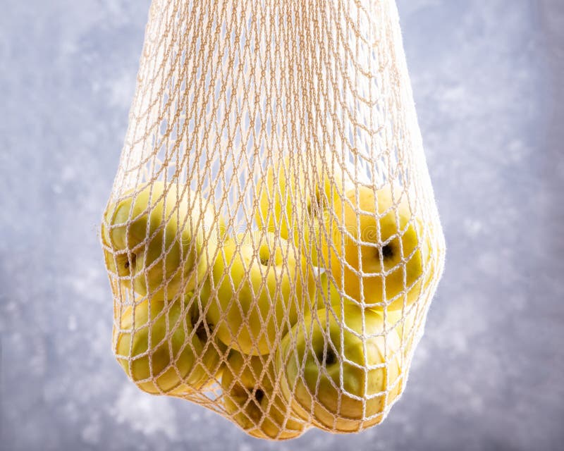Yellow Apples in White Mesh Bag Against Gray Wall. Zero Waste Concept ...