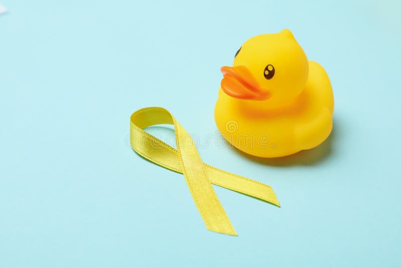 Yellow Awareness Ribbon and Rubber Duck on Blue Background Stock Photo ...