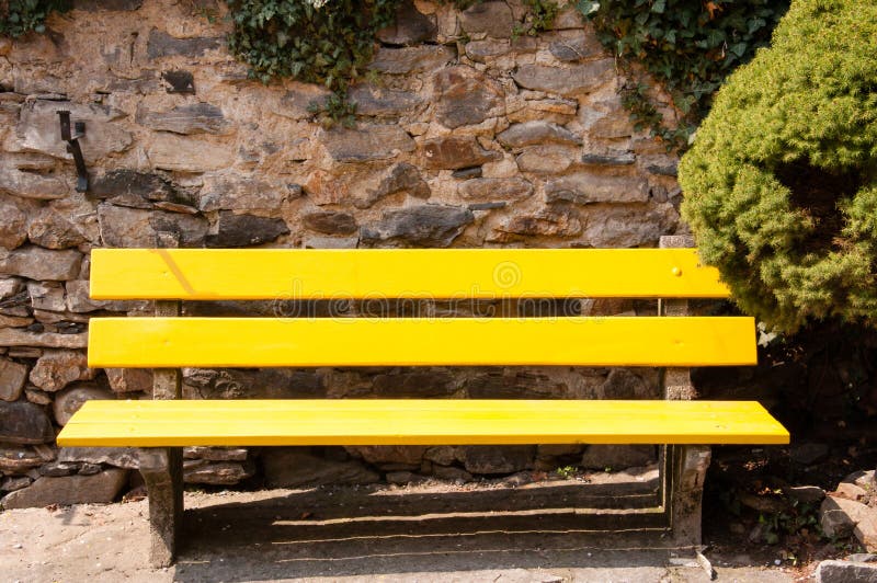 Yellow Bench in Front of Stone Wall Stock Photo - Image of park, bench ...