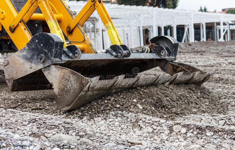 A Yellow and Black Construction Machine is Digging into the Ground ...