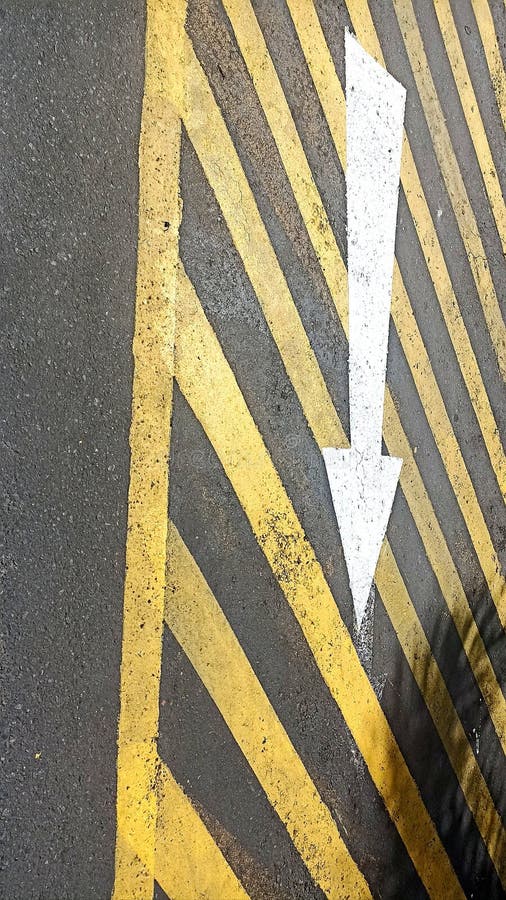 Yellow and Black Diagonal Stripes with a White Arrow on Asphalt. Stock ...