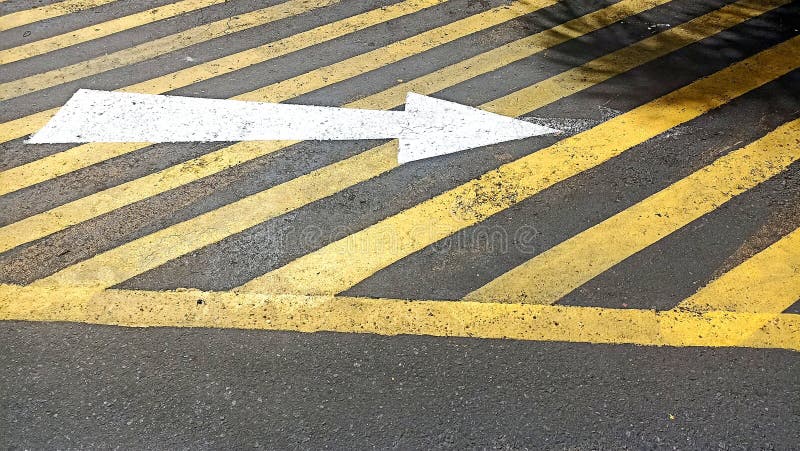 Yellow and Black Diagonal Stripes with a White Arrow on Asphalt. Stock ...