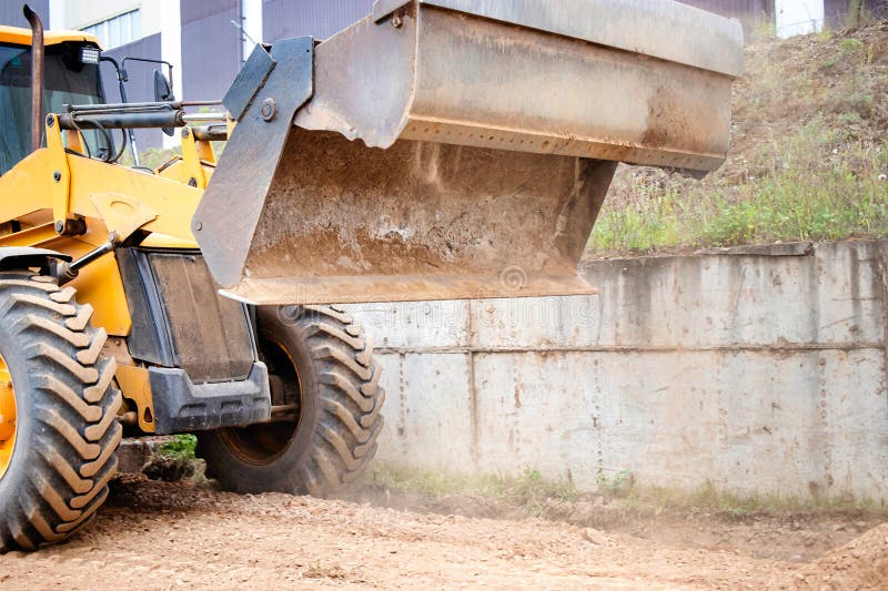 A Yellow Bulldozer or a Loader is Parked in Front of a Building, Ready ...