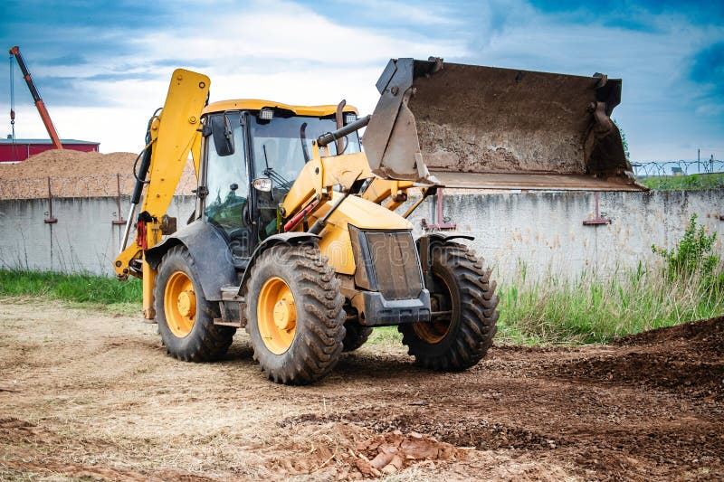 A Yellow Bulldozer or a Loader is Parked Next To a Building, Ready for ...