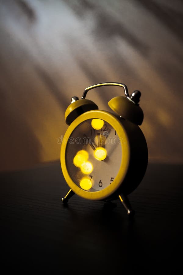 Office Clock on a Black Desk Shownig Time. Yellow Clock on a Dark ...