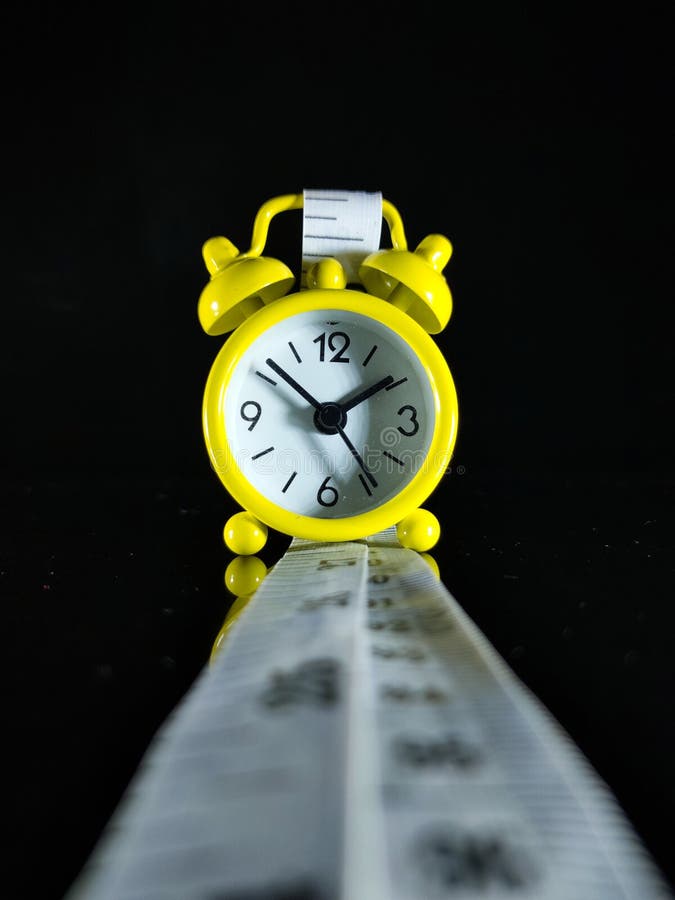 A Yellow Clock and Measuring Tape on a Black Background. Stock Photo ...