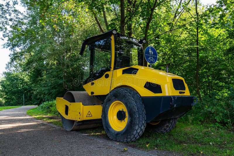A Yellow Construction Roller Standing on the Side of a Path in the Park ...