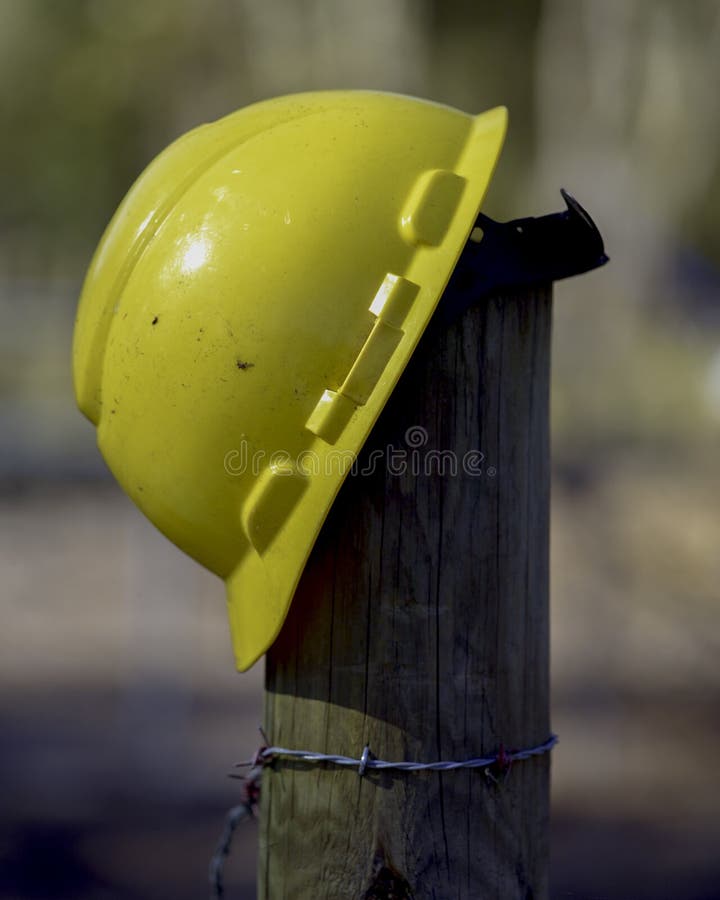 A Yellow Construction Workers Helmet on an Old Fence Post Stock Photo ...
