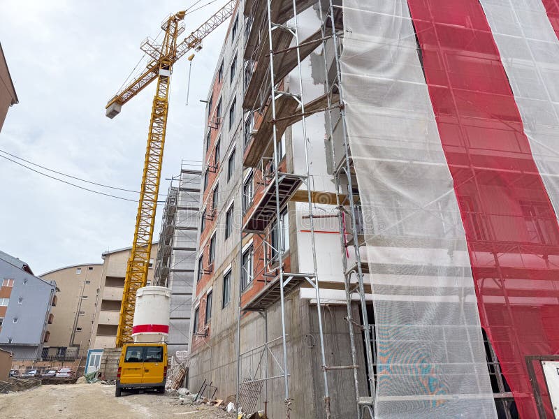 Yellow Crane and Scaffolding on Urban Building Site. Protective Mesh ...