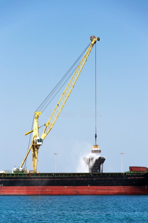 Yellow Crane Unloading Sand from Large Freighter Cargo Ship in Harbor ...
