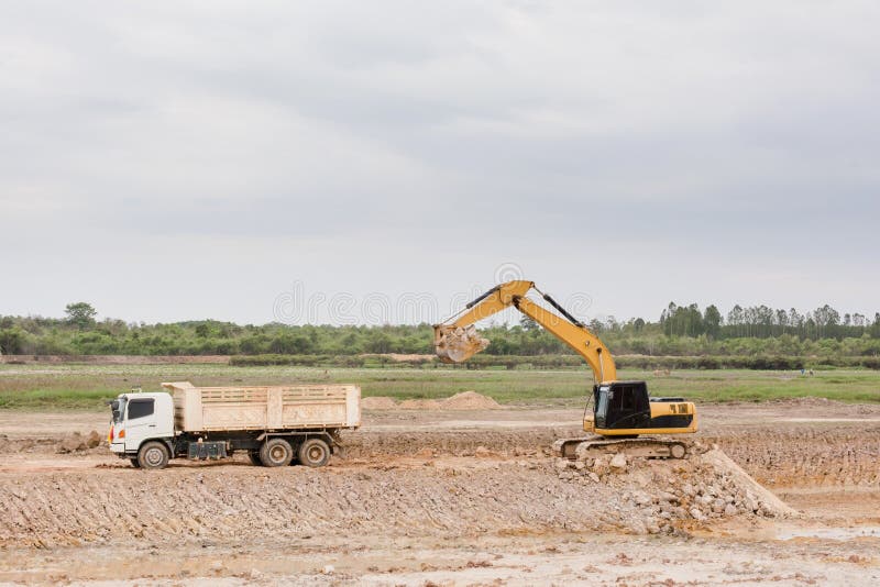 Yellow Excavator Machine Loading Soil into a Dump Truck at Construction ...