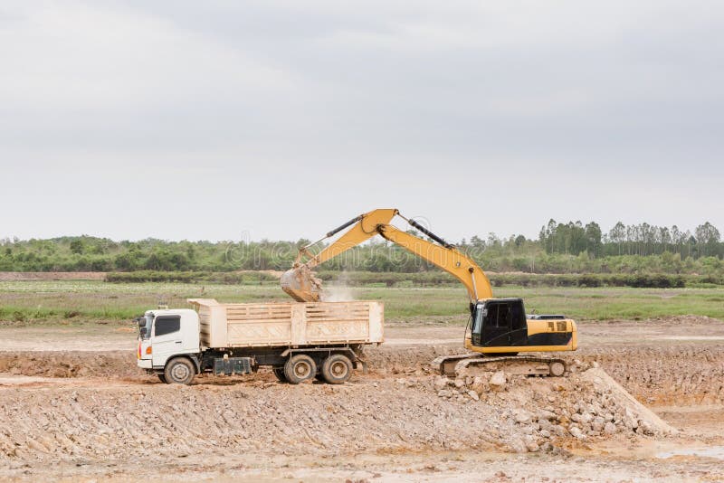Yellow Excavator Machine Loading Soil into a Dump Truck at Construction ...