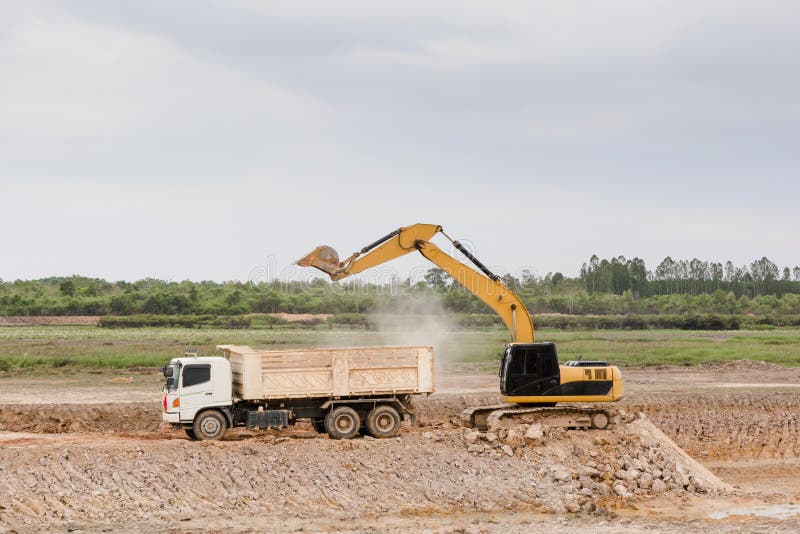 Yellow Excavator Machine Loading Soil into a Dump Truck at Construction ...