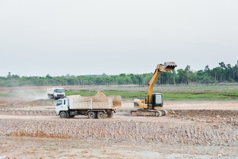 Yellow Excavator Machine Loading Soil into a Dump Truck at Construction ...