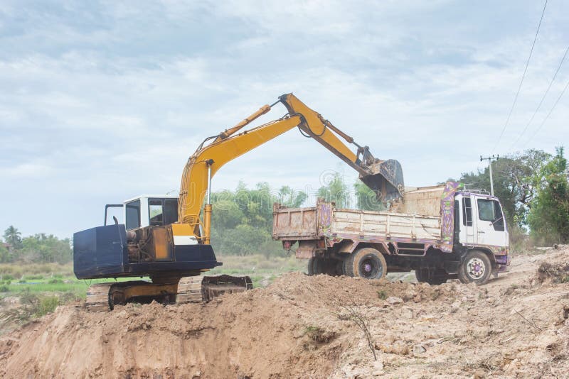 Yellow Excavator Machine Loading Soil into a Dump Truck at Construction ...