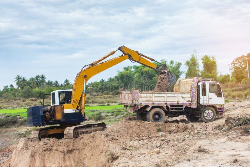 Yellow Excavator Machine Loading Soil into a Dump Truck at Construction ...