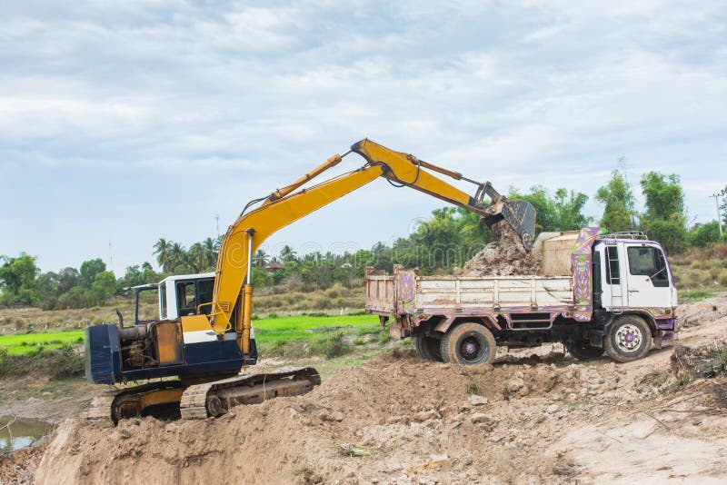 Yellow Excavator Machine Loading Soil into a Dump Truck at Construction ...