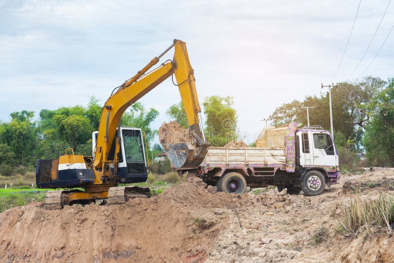 Yellow Excavator Machine Loading Soil into a Dump Truck at Construction ...