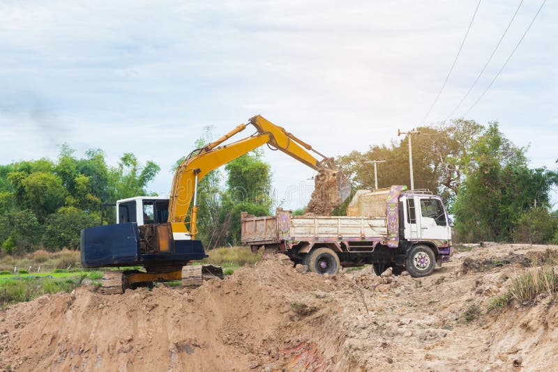 Yellow Excavator Machine Loading Soil into a Dump Truck at Construction ...