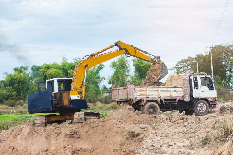 Yellow Excavator Machine Loading Soil into a Dump Truck at Construction ...