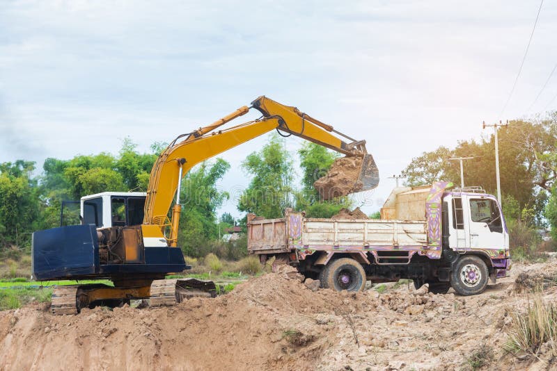 Yellow Excavator Machine Loading Soil into a Dump Truck at Construction ...