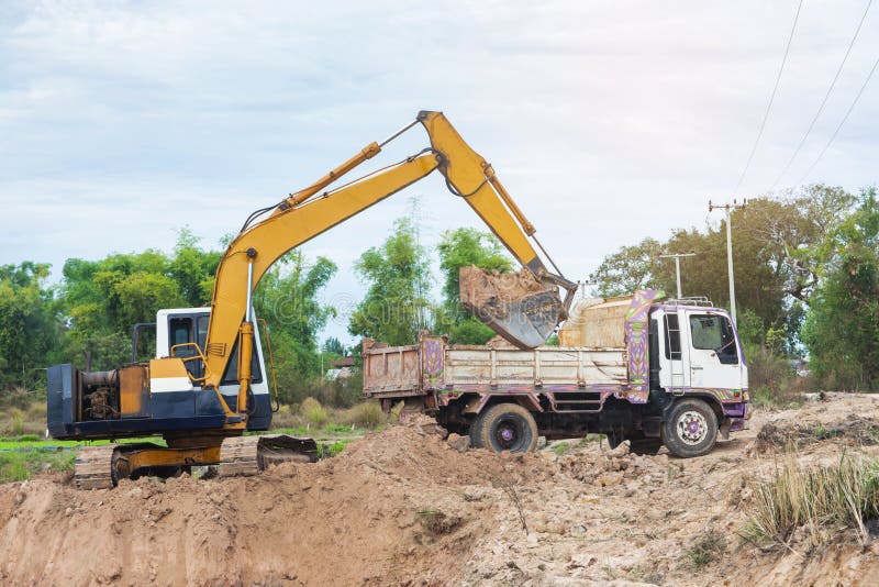 Yellow Excavator Machine Loading Soil into a Dump Truck at Construction ...