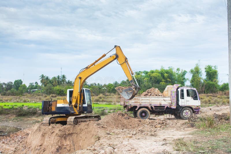 Yellow Excavator Machine Loading Soil into a Dump Truck at Construction ...