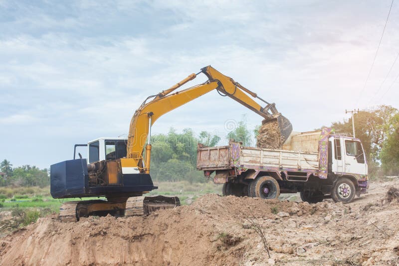 Yellow Excavator Machine Loading Soil into a Dump Truck at Construction ...