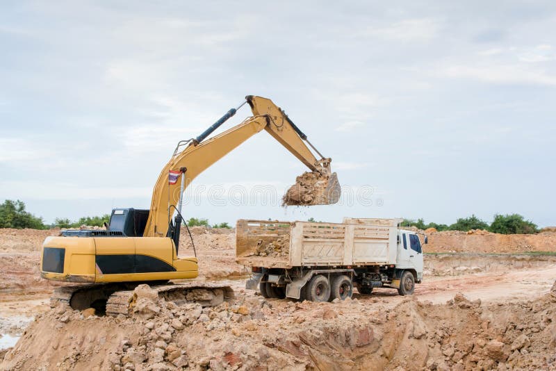Yellow Excavator Machine Loading Soil into a Dump Truck at Construction ...