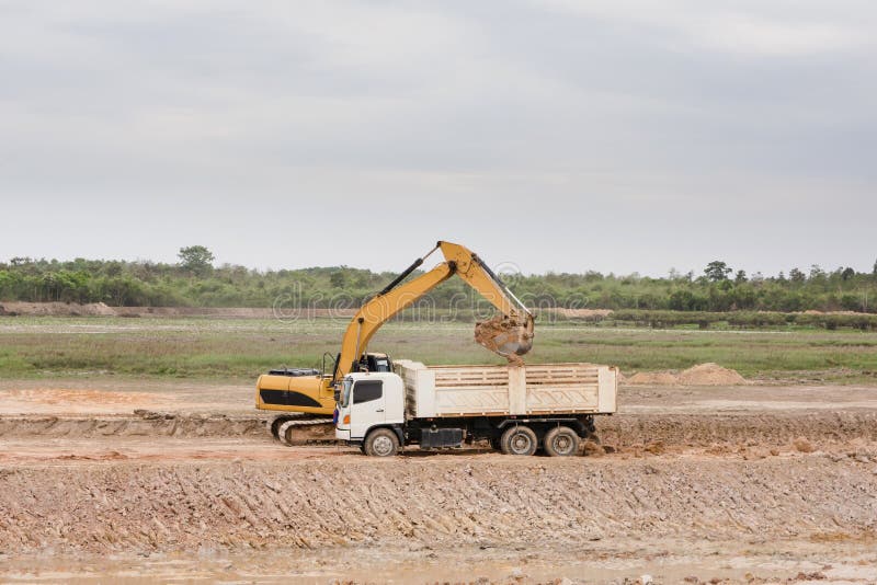 Yellow Excavator Machine Loading Soil into a Dump Truck at Construction ...