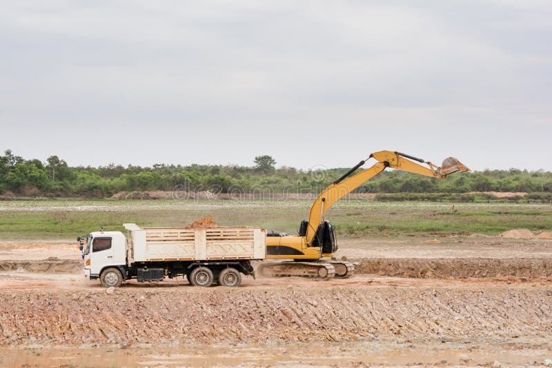 Yellow Excavator Machine Loading Soil into a Dump Truck at Construction ...