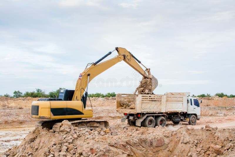 Yellow Excavator Machine Loading Soil into a Dump Truck at Construction ...