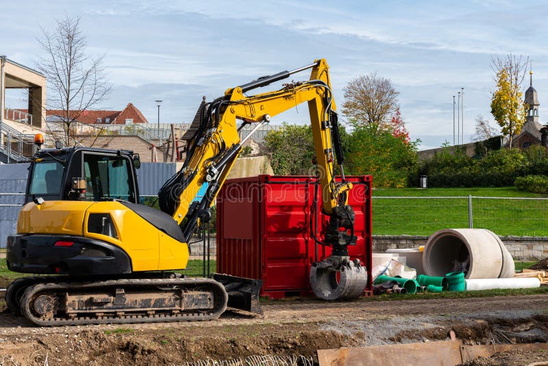 Yellow Excavator and Truck on a Construction Site between Buildings ...
