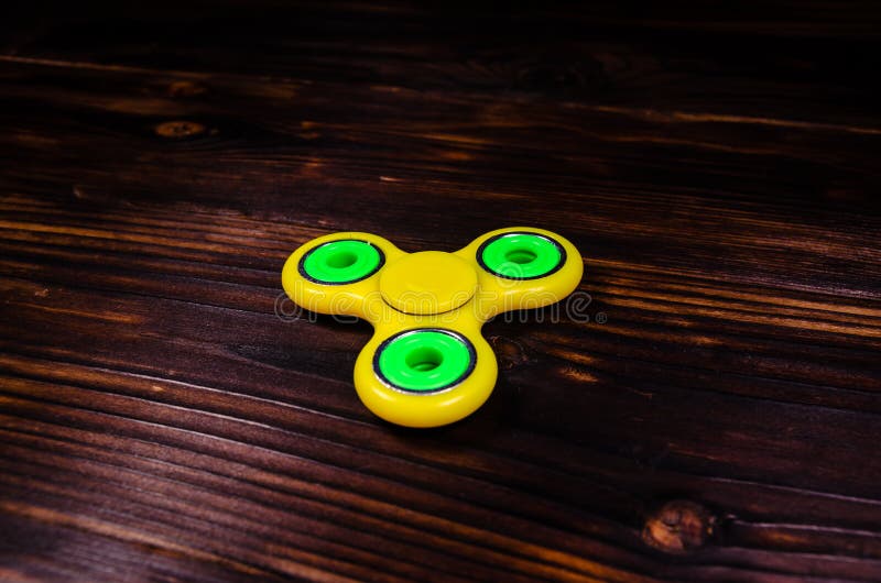 Yellow Fidget Spinner on Wooden Desk Stock Image - Image of hand ...