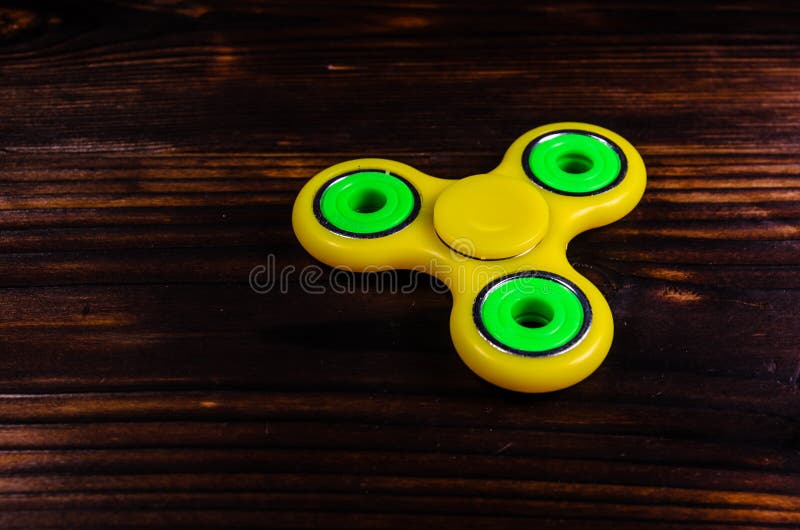 Yellow Fidget Spinner on Wooden Desk Stock Image - Image of closeup ...