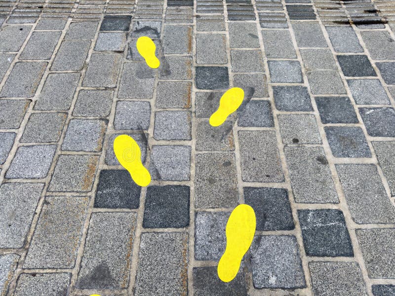 Yellow Footprints on Cobblestone Pavement Highlighting Urban Pathway ...