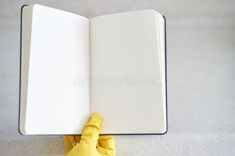 Yellow Gloved Hand Holding Open Blank Notebook on Light Granite Surface ...