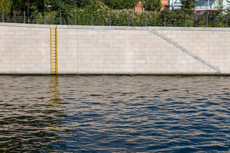 Yellow Ladder on a Concrete Block Wall on the Edge of the River Stock ...
